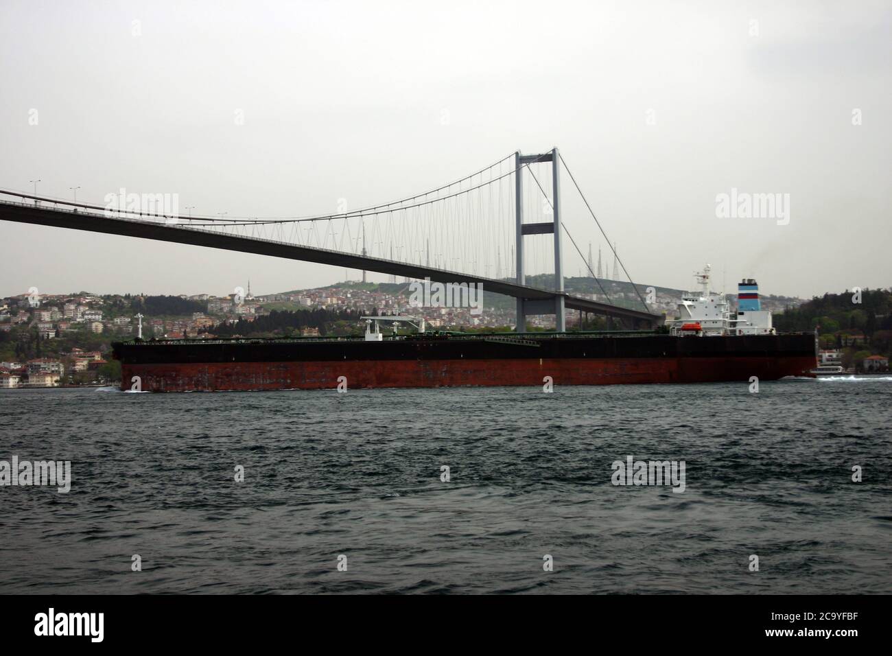 A big oil tanker passing under the bridge in the Bosphorus. The ...