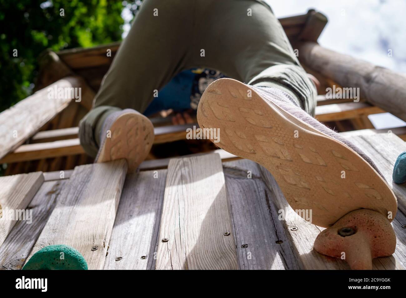 Person clambering up a wooden climbing frame in a view from directly ...