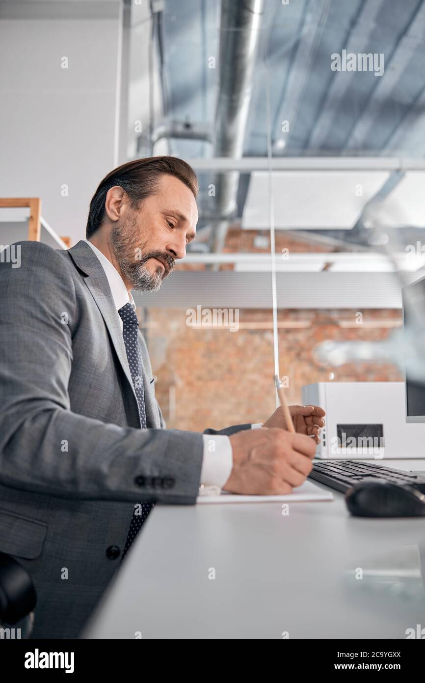 Bearded man writing in notebook at work Stock Photo - Alamy