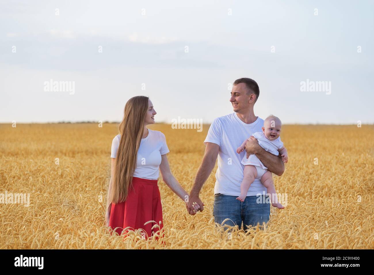 Young happy family resting in countryside. Mom dad and kid in wheat ...