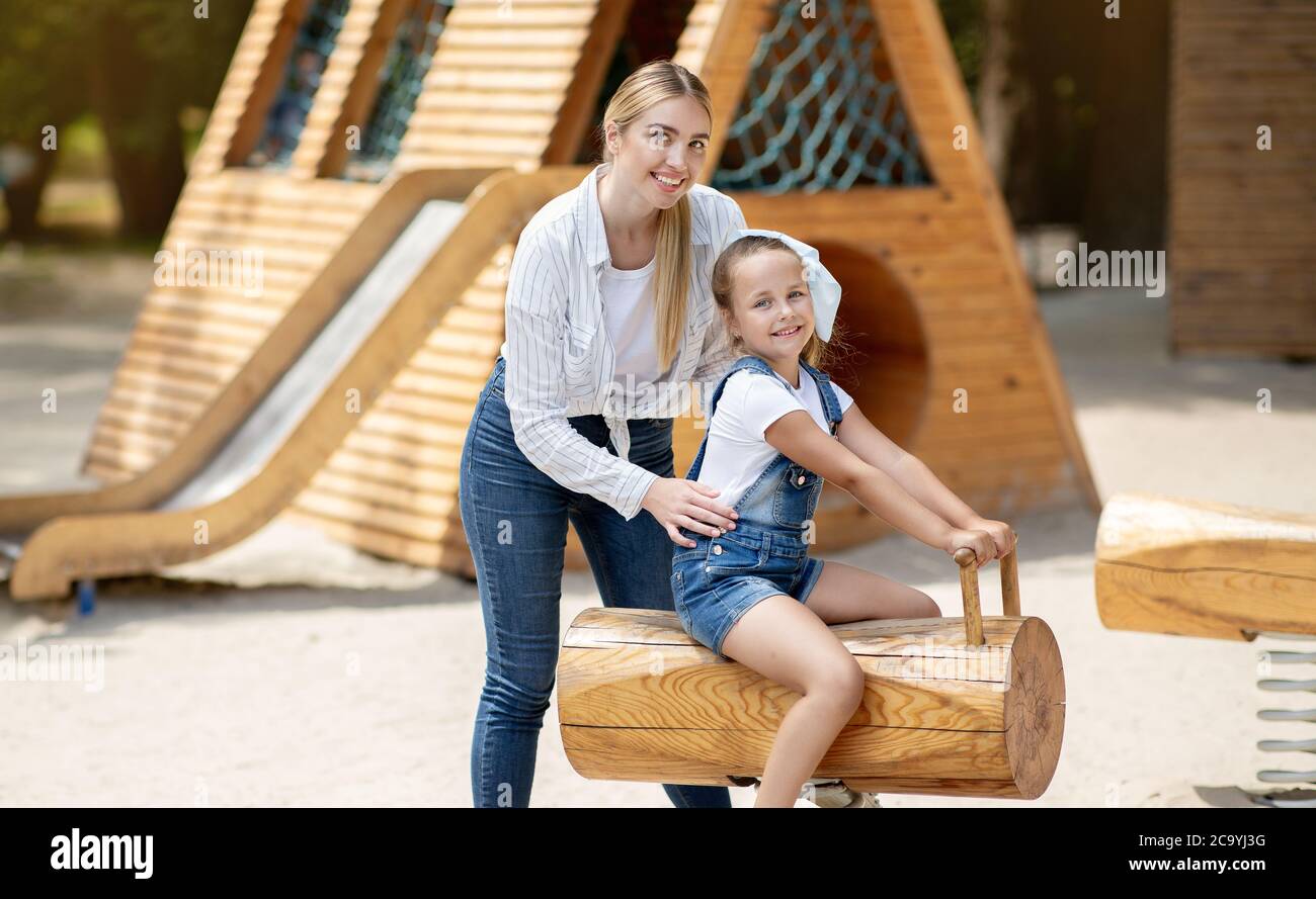 Mother Pushing Little Daughter On Swing Spending Time On Playground Stock Photo - Alamy