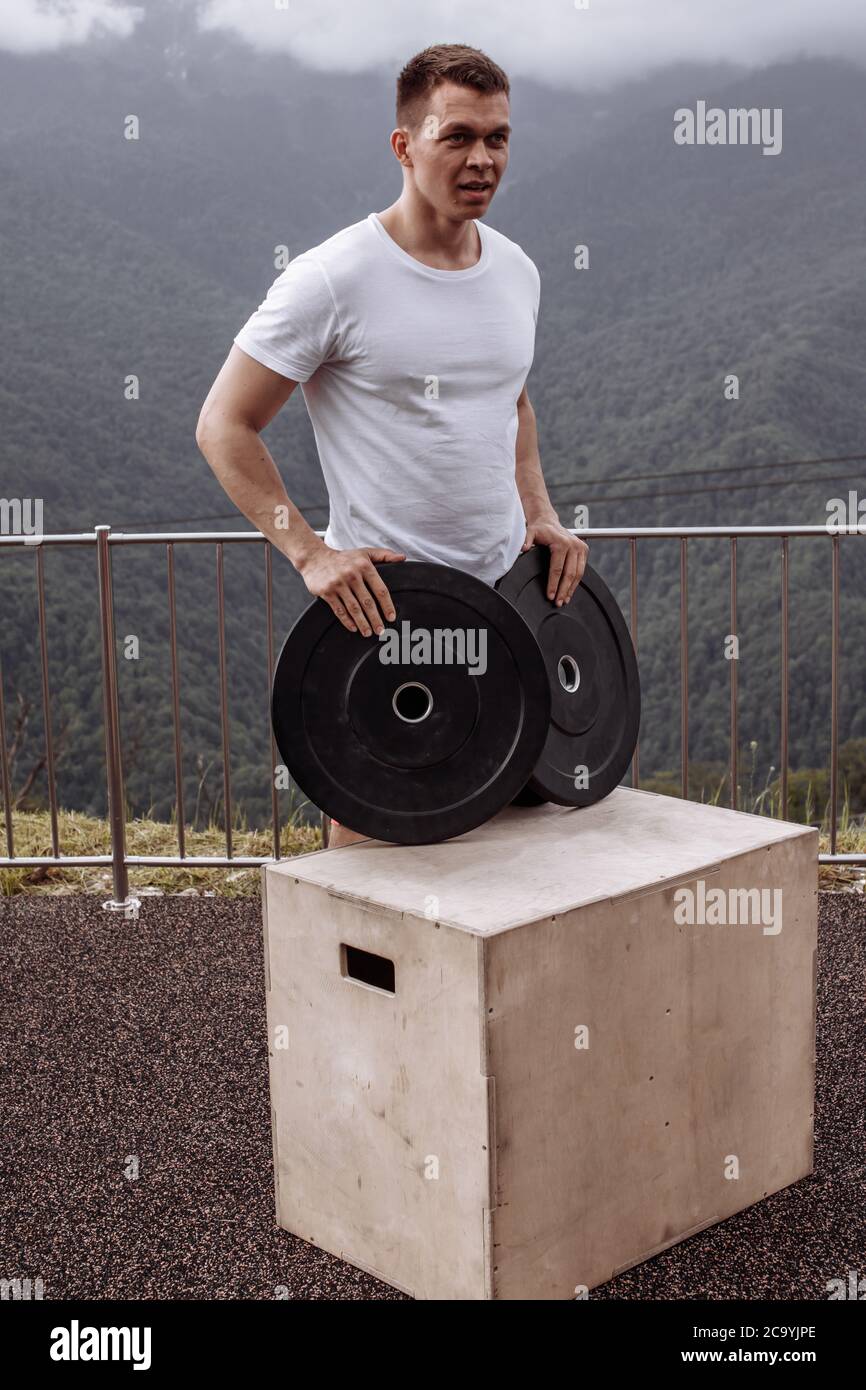 Strong caucasian crossfit male instructor posing with barbell plate ...