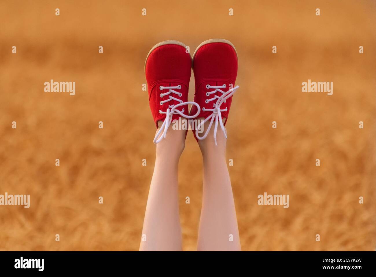 feet in red shoes upwards. Slender female legs on wheat field ...