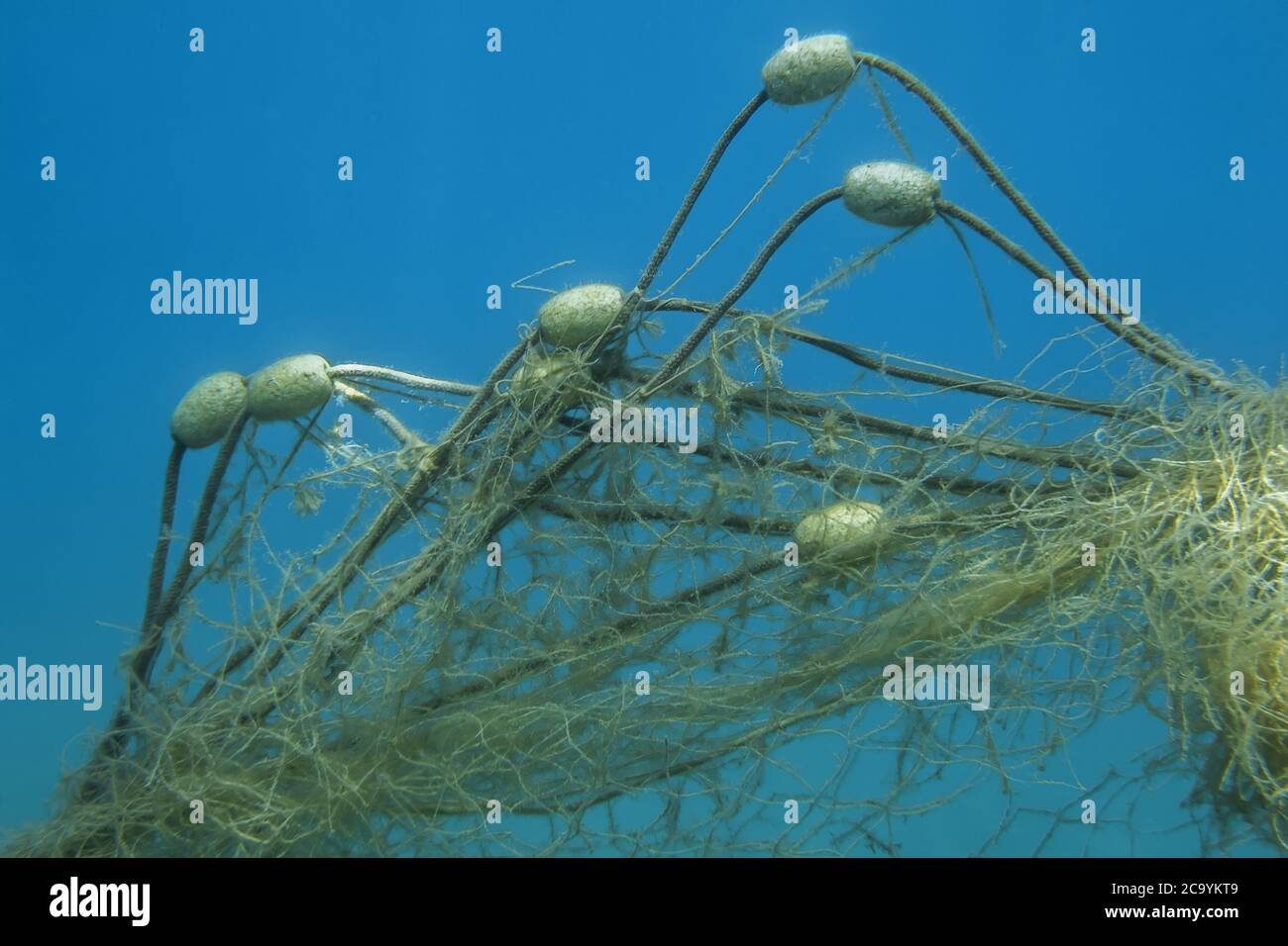 Lost fishing net with buoys lies underwater on the seabed on blue water ...