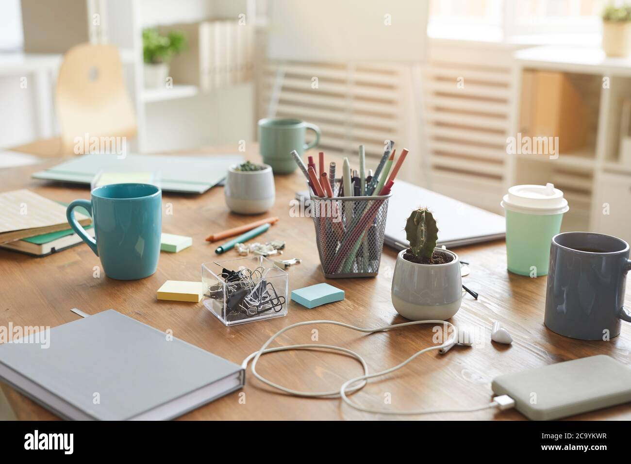 Background image of cluttered workplace table with cups, mugs and ...