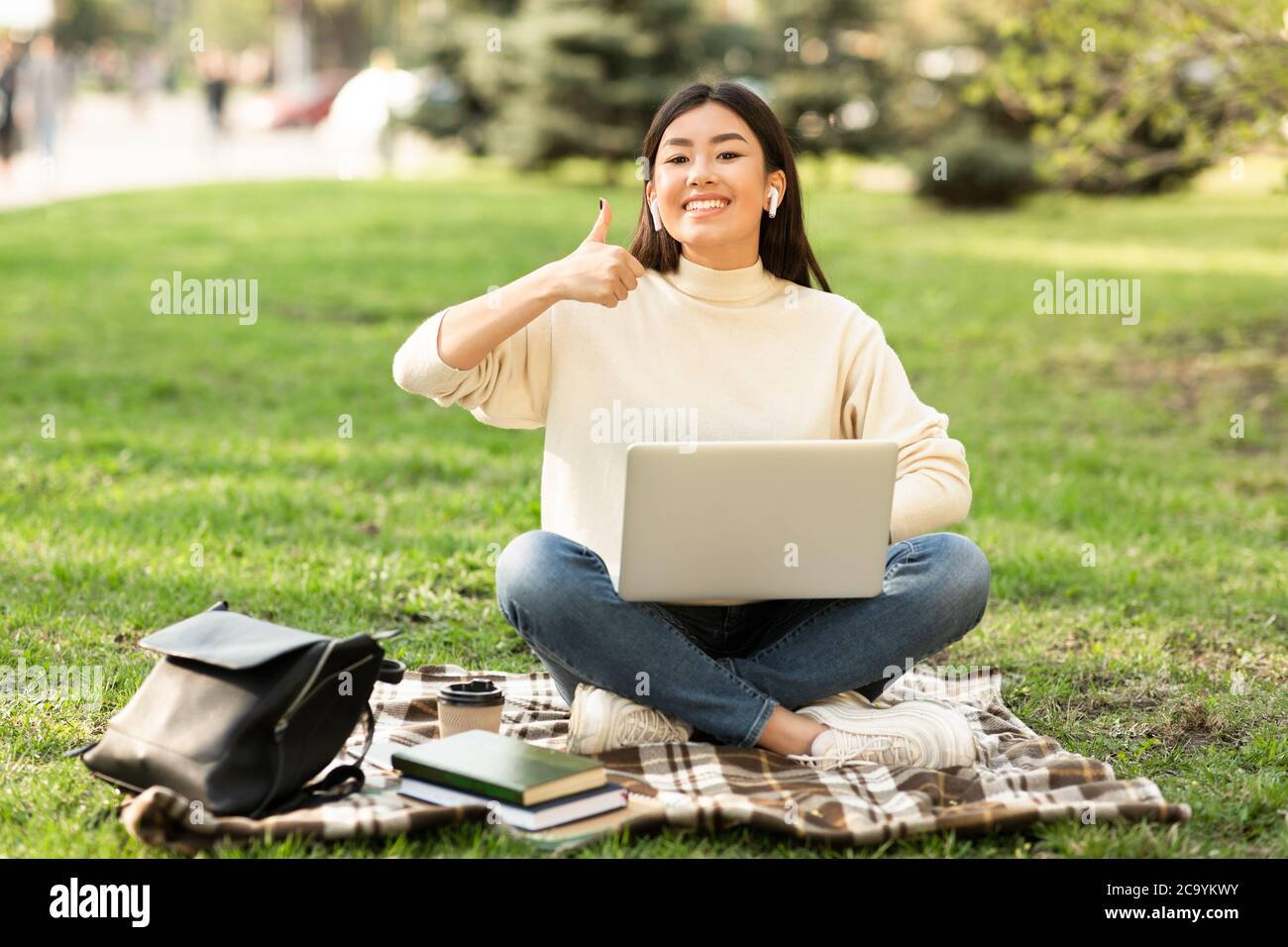 Student using laptop, sitting in the parkland Stock Photo - Alamy