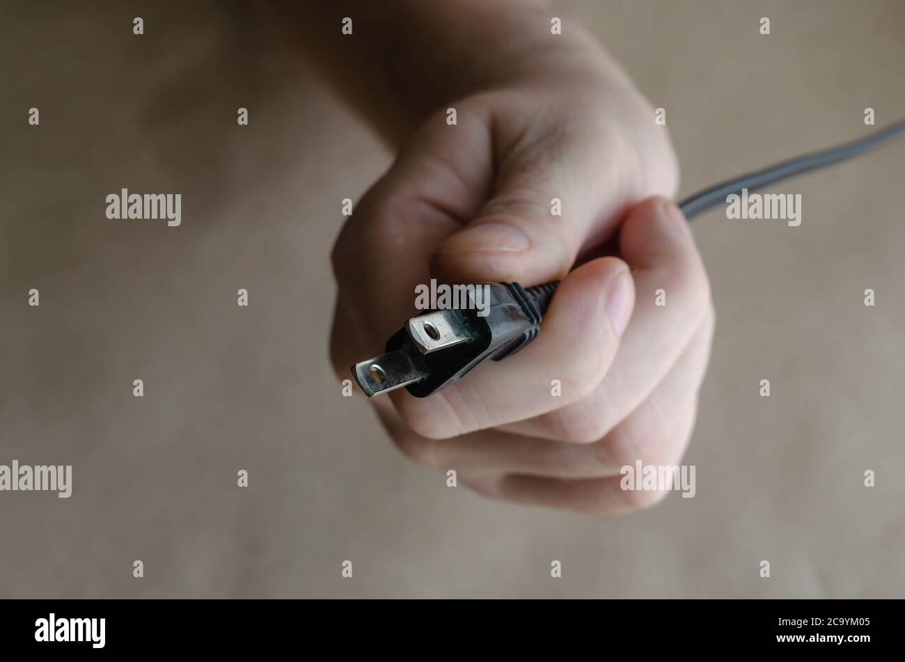 Hand of an adult Caucasian male is holding black electric plug. DC ...