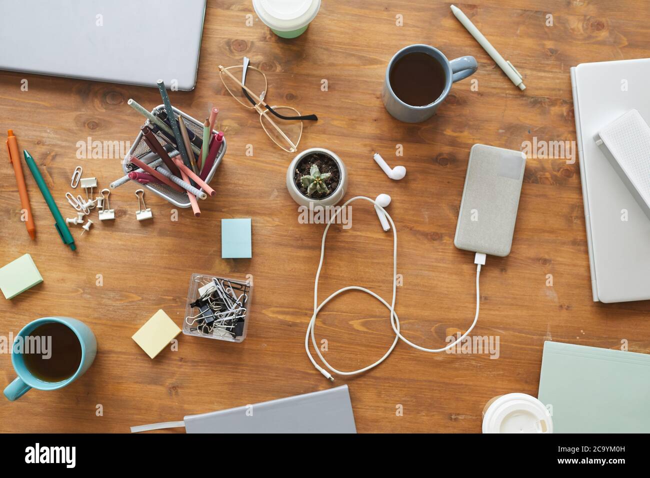 Top view background image of cluttered workplace table with cups, mugs ...