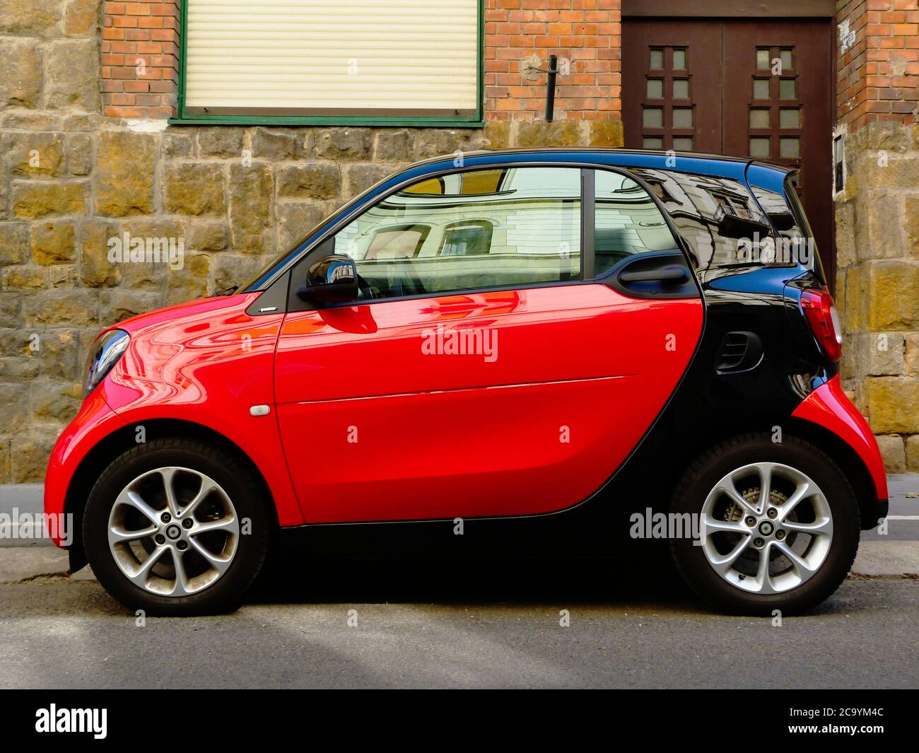 red and black modern compact town car in side view in old urban setting ...
