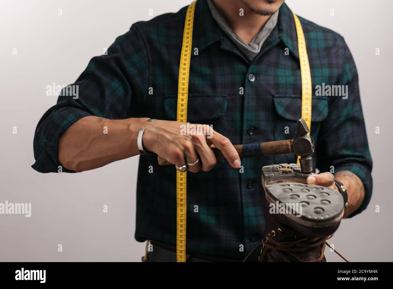 Isolated studio shot of unrecognizable shoemaker with measure tape on ...