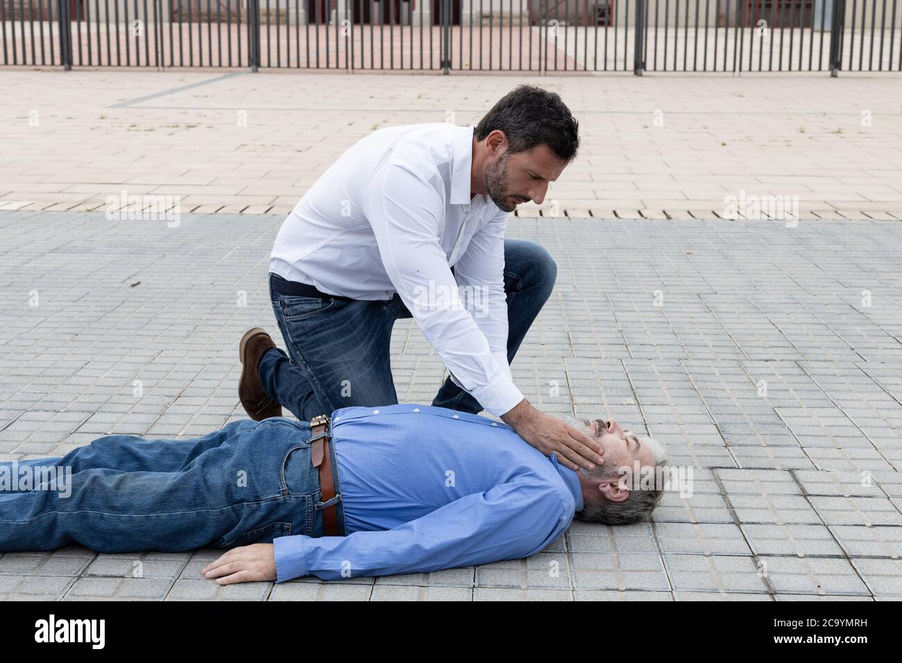 Young male helping an unconscious man outdoors - first aid concept ...