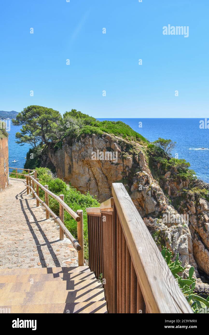 Staircase on a cliff surrounded by handrails and the sea under a blue ...