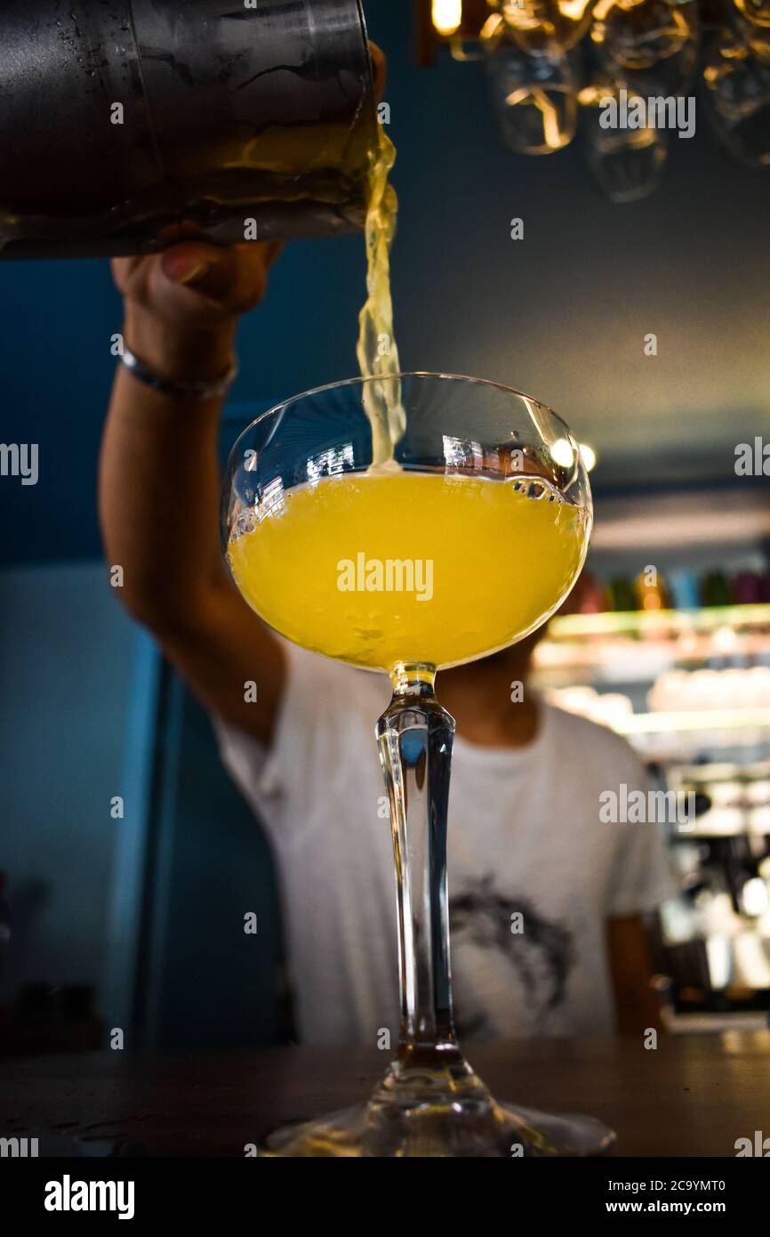 Vertical shot of a barman pouring a delicious cocktail in a glass on ...