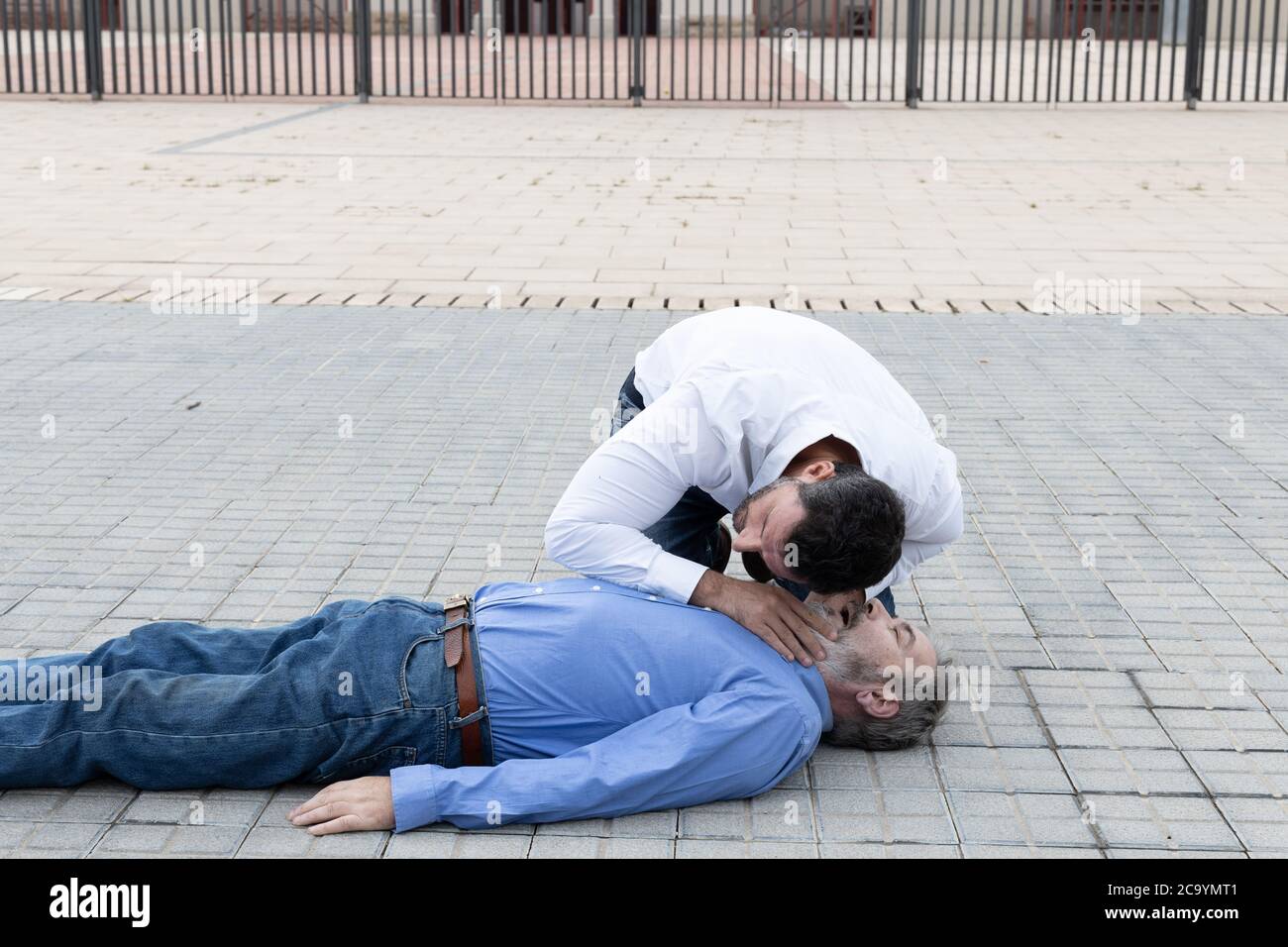 Young male helping an unconscious man outdoors - first aid concept ...
