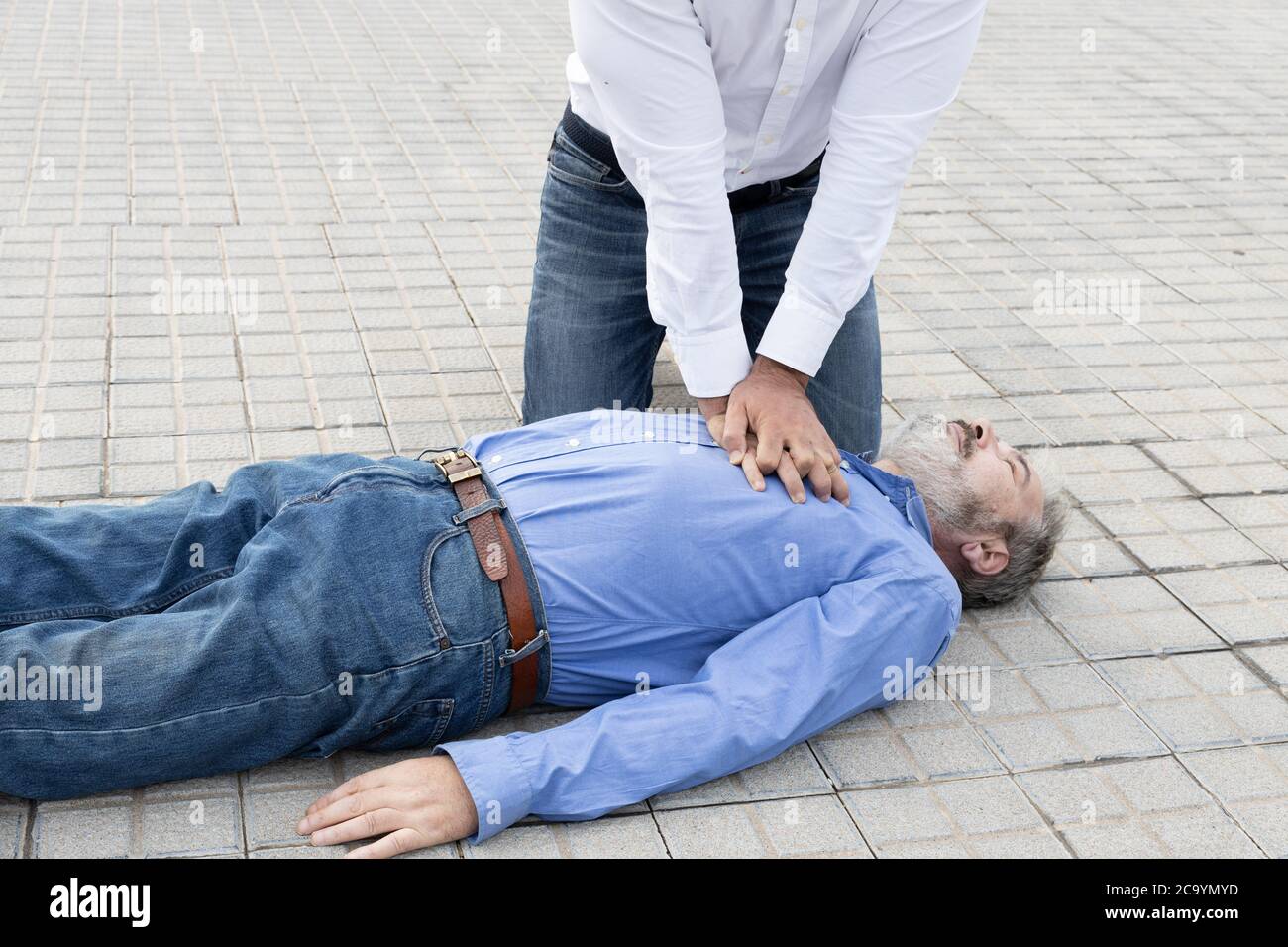Young male helping an unconscious man outdoors - first aid concept ...