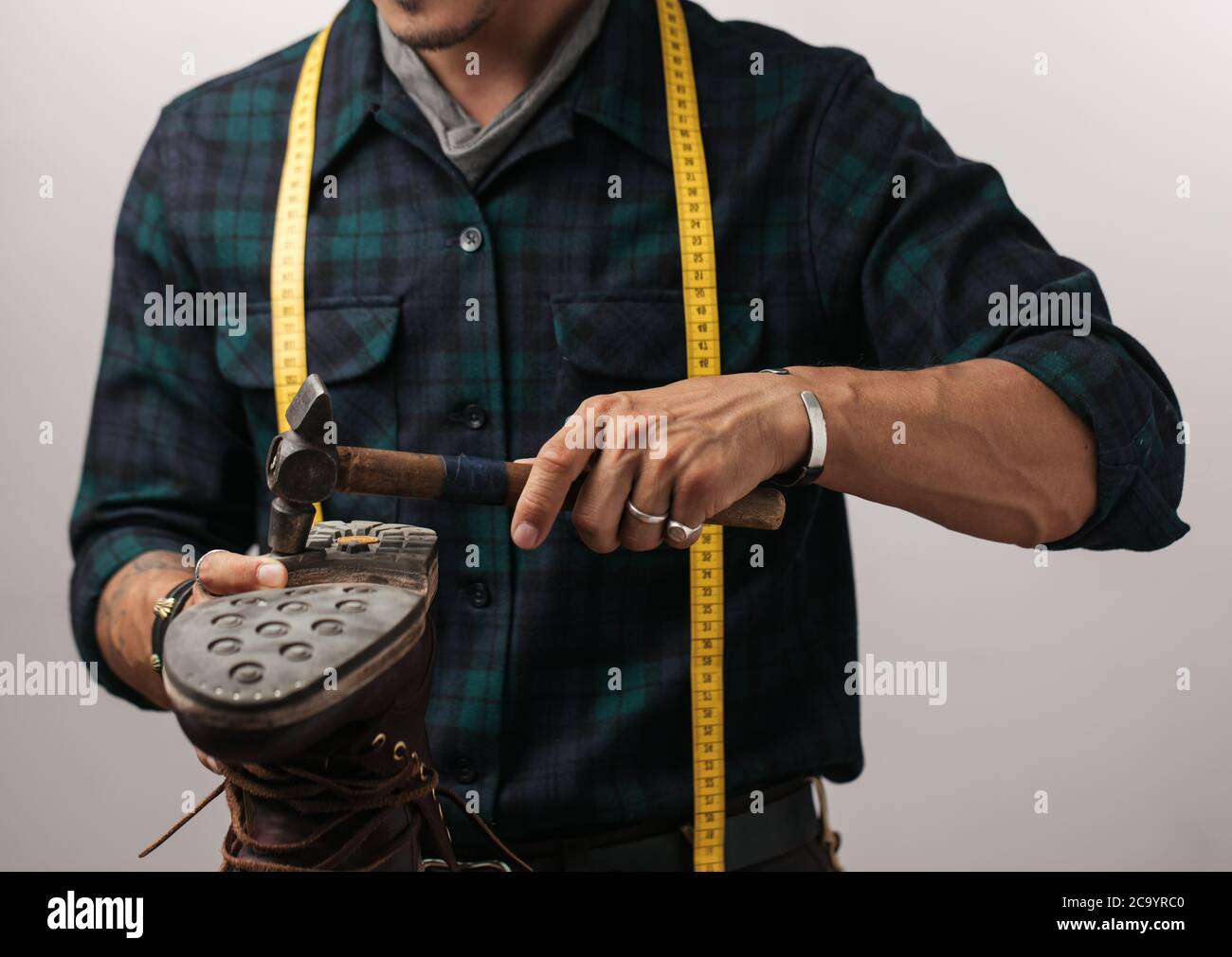 Cropped image of a shoemaker with measuring tape, working with of a ...