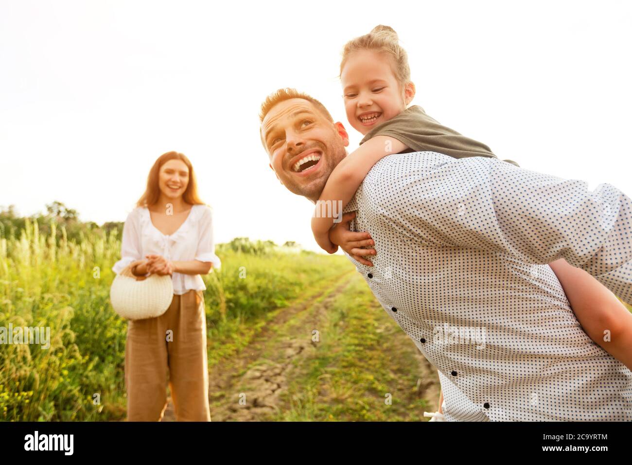 Cheerful dad piggybacking his little baby in countryside Stock Photo ...