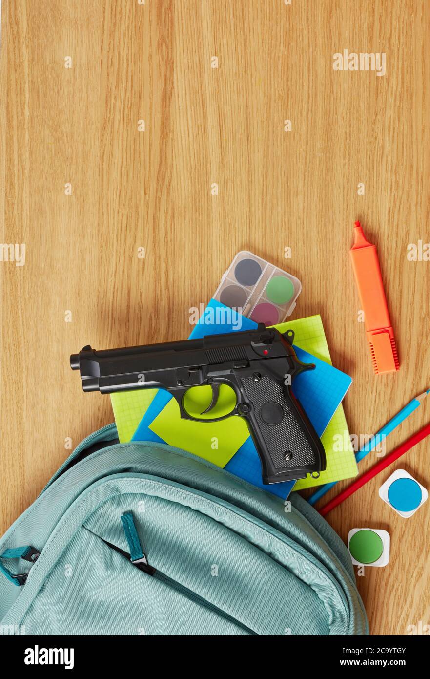 Backpack, school supplies and gun on desk Stock Photo - Alamy