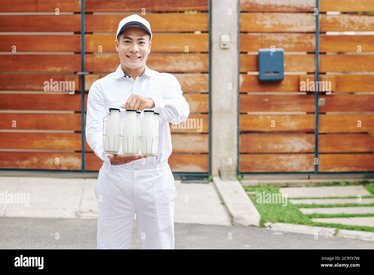 Happy yuong Asian milkman offering fresh milk in glass bottles Stock ...