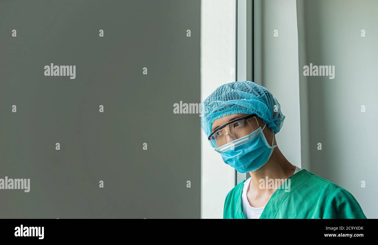 Tired doctor at the hospital looking through a window. The fight ...