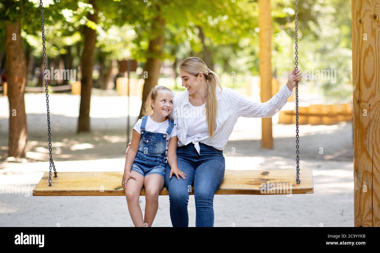 Mother And Little Daughter Swinging On Swings On Outdoor Playground Stock Photo - Alamy