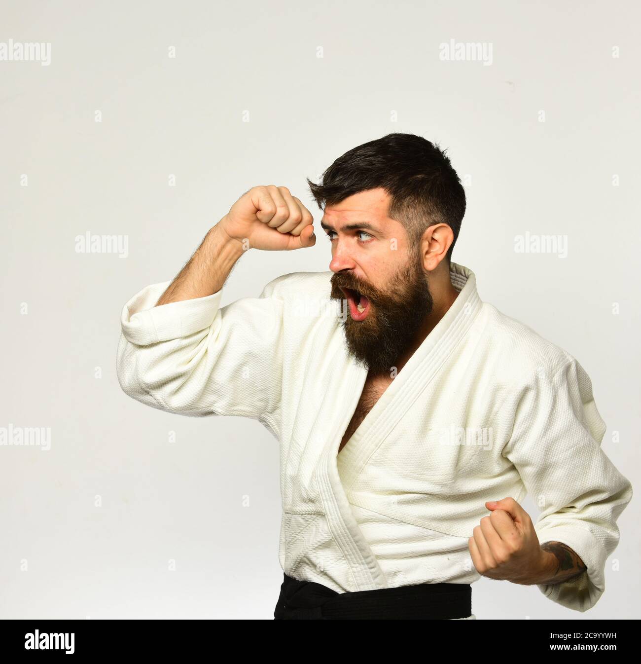 Man with beard in white kimono on white background. Judo master defends ...