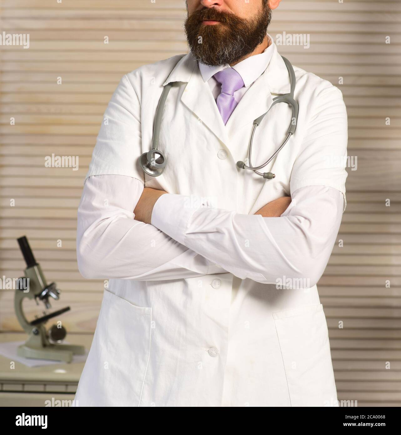 Doctor in white medical coat holds hands crossed. Man in surgical ...