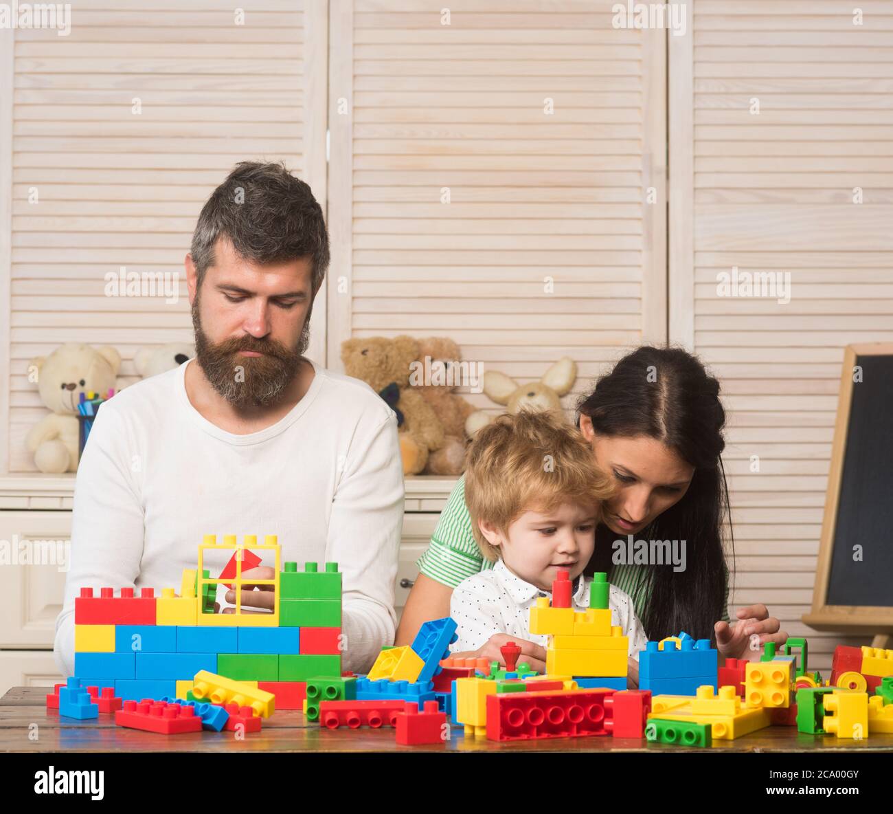 Family playing with plastic blocks. Parents and kid with concentrated ...