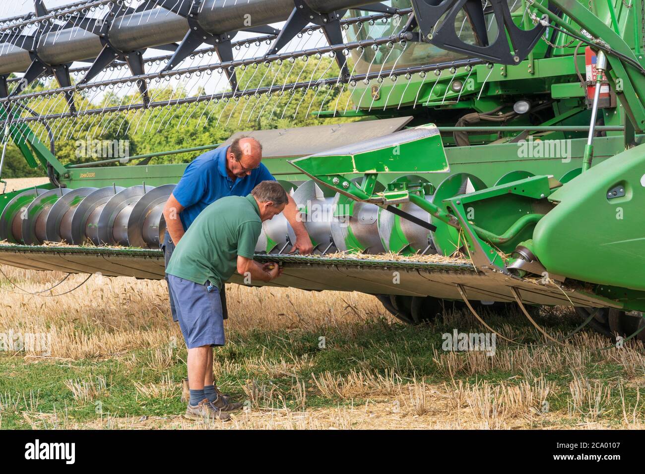 Stationary combine harvester, with two men undertaking basic ...