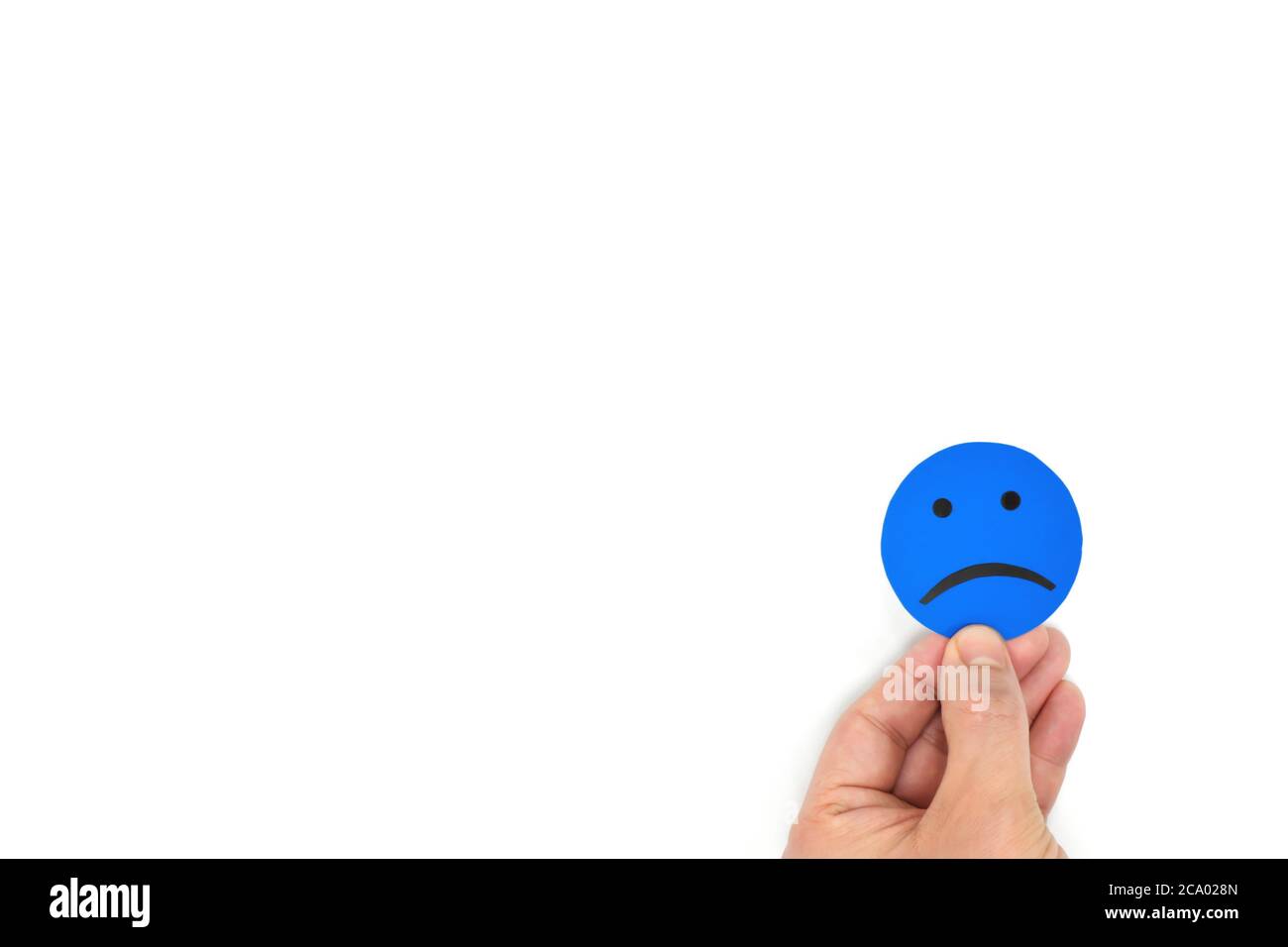 Male hand holding a blue sad face icon in white background with copy ...