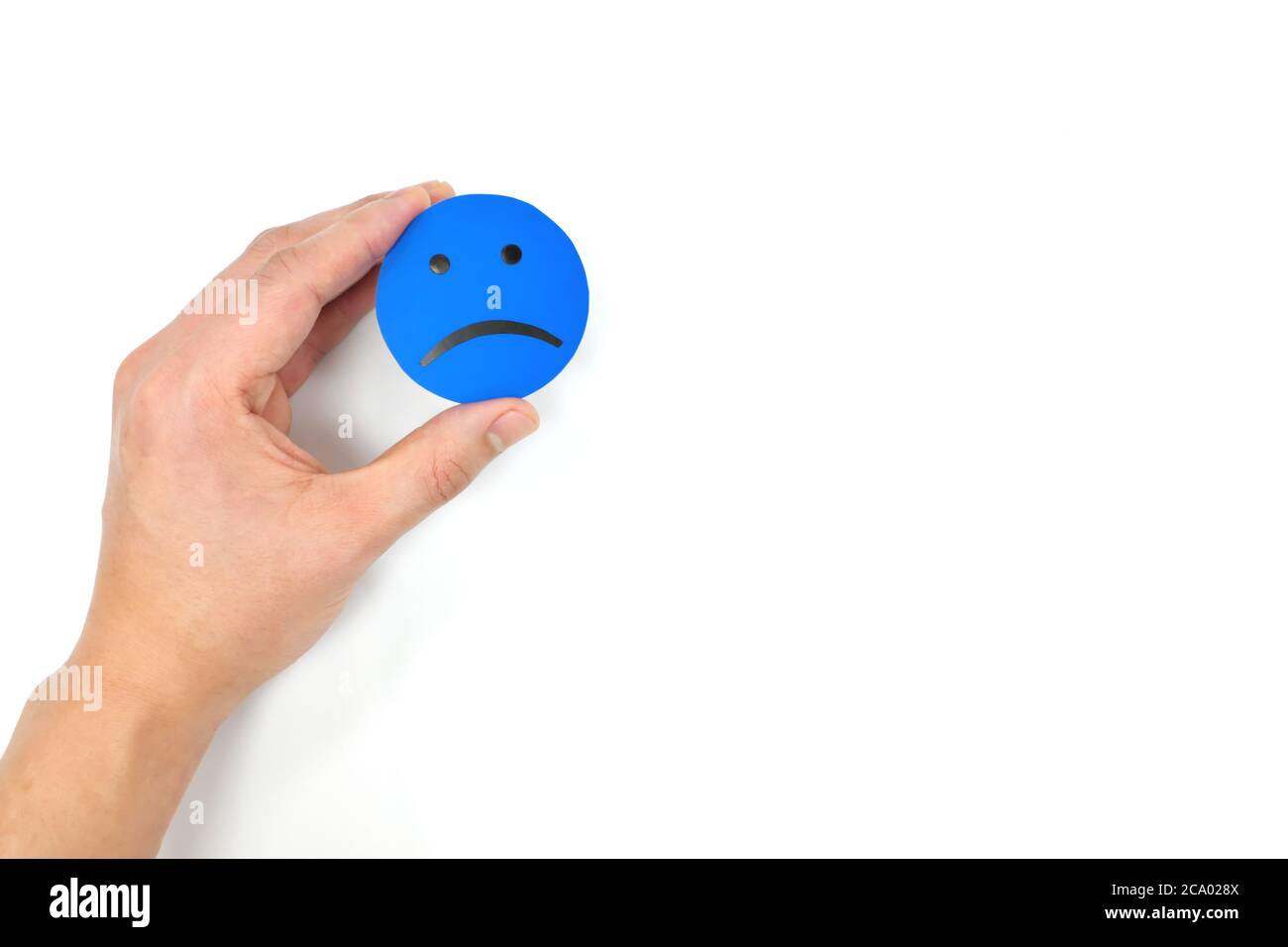 Male hand holding a blue sad face icon in white background with copy ...
