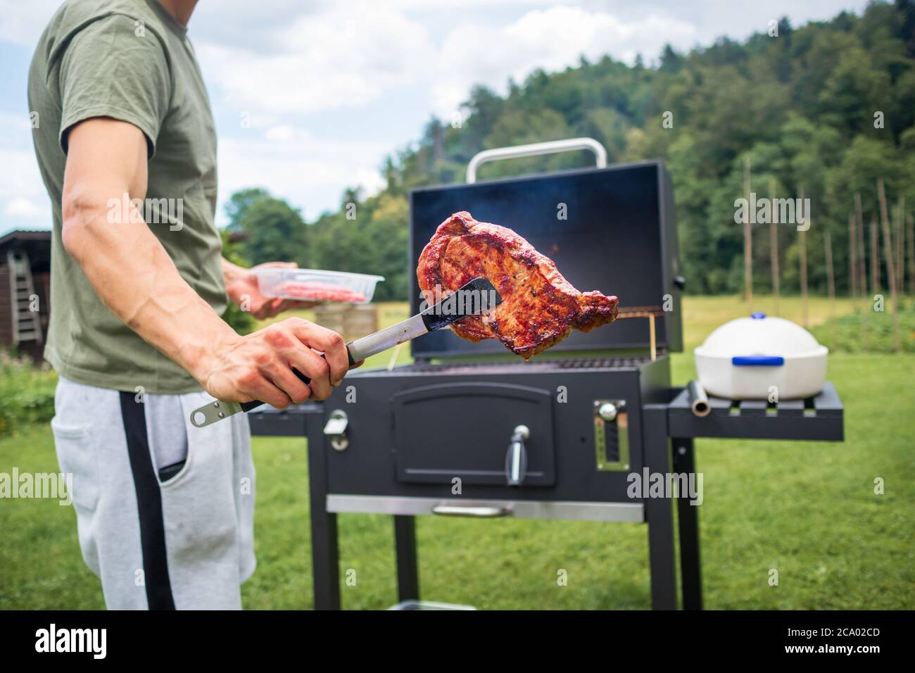 Home barbecue with charcoal in the backyard grilling steaks and other ...
