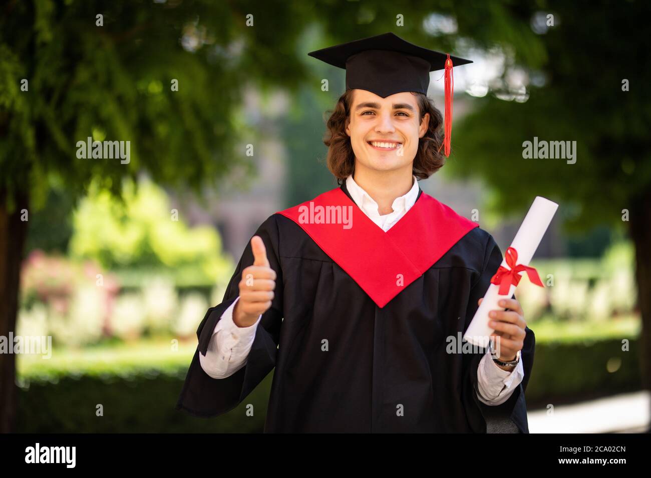 Graduation student standing with diploma with friends behind Stock ...