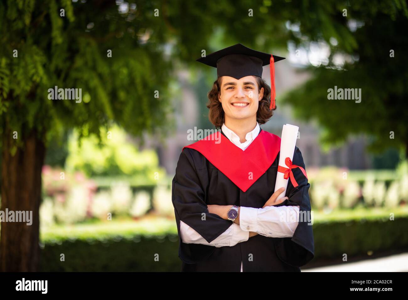Graduation student standing with diploma with friends behind Stock ...