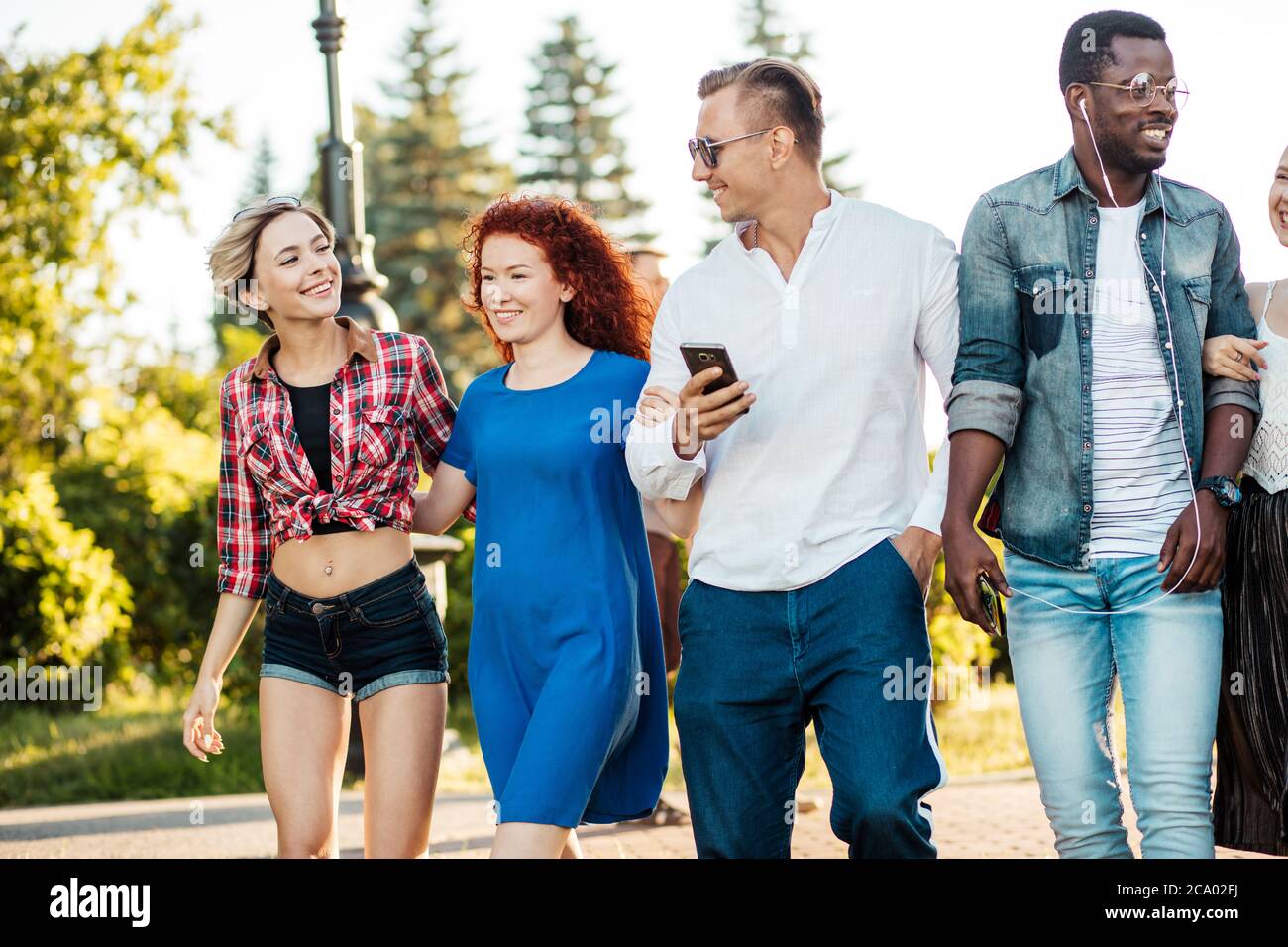 Multi-ethnic group of young cheerful people bonding outdoors, having a ...