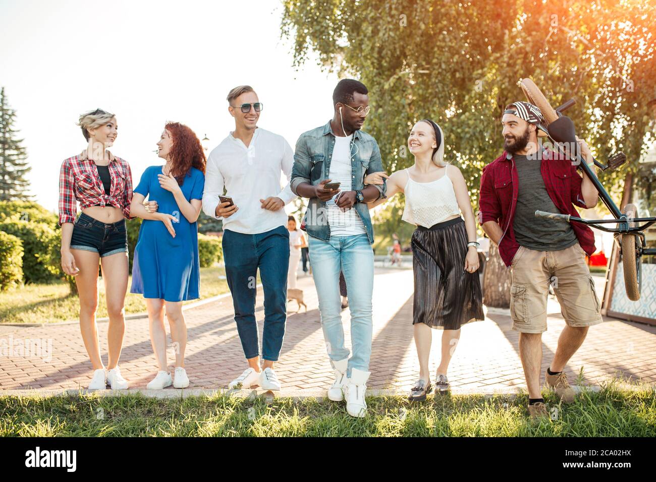Happy adult guys and girls in casual wear enjoying a long walk ...