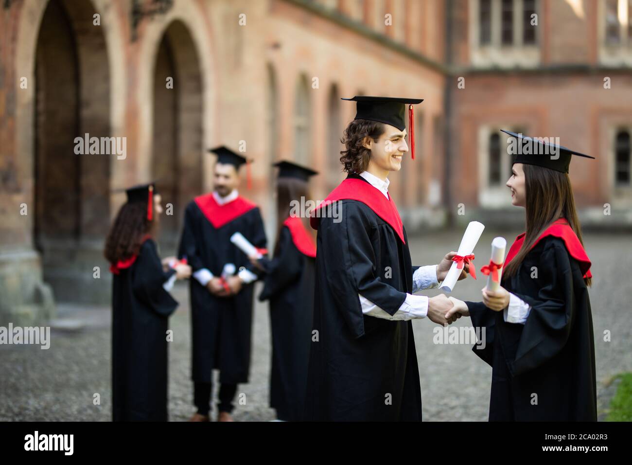 Close-up of a smiling graduate smiling with her friends in background ...