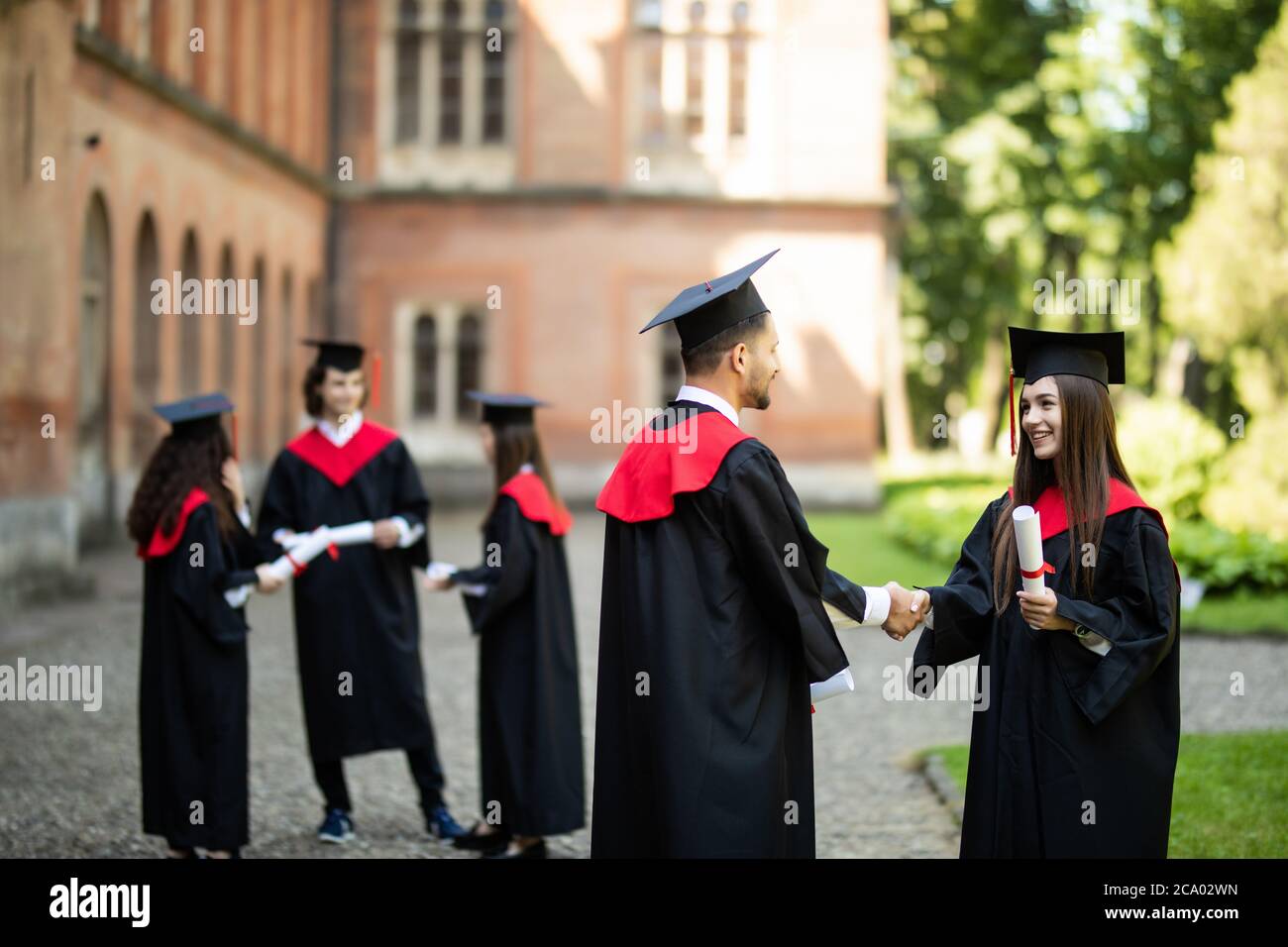 Close-up of a smiling graduate smiling with her friends in background ...