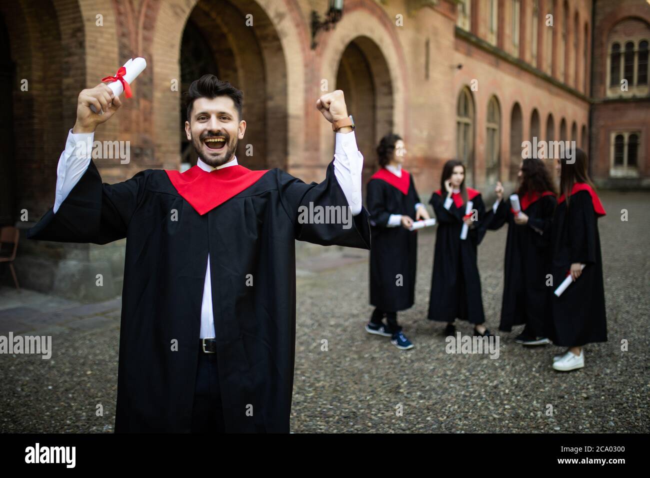 Close-up of a smiling graduate smiling with her friends in background ...
