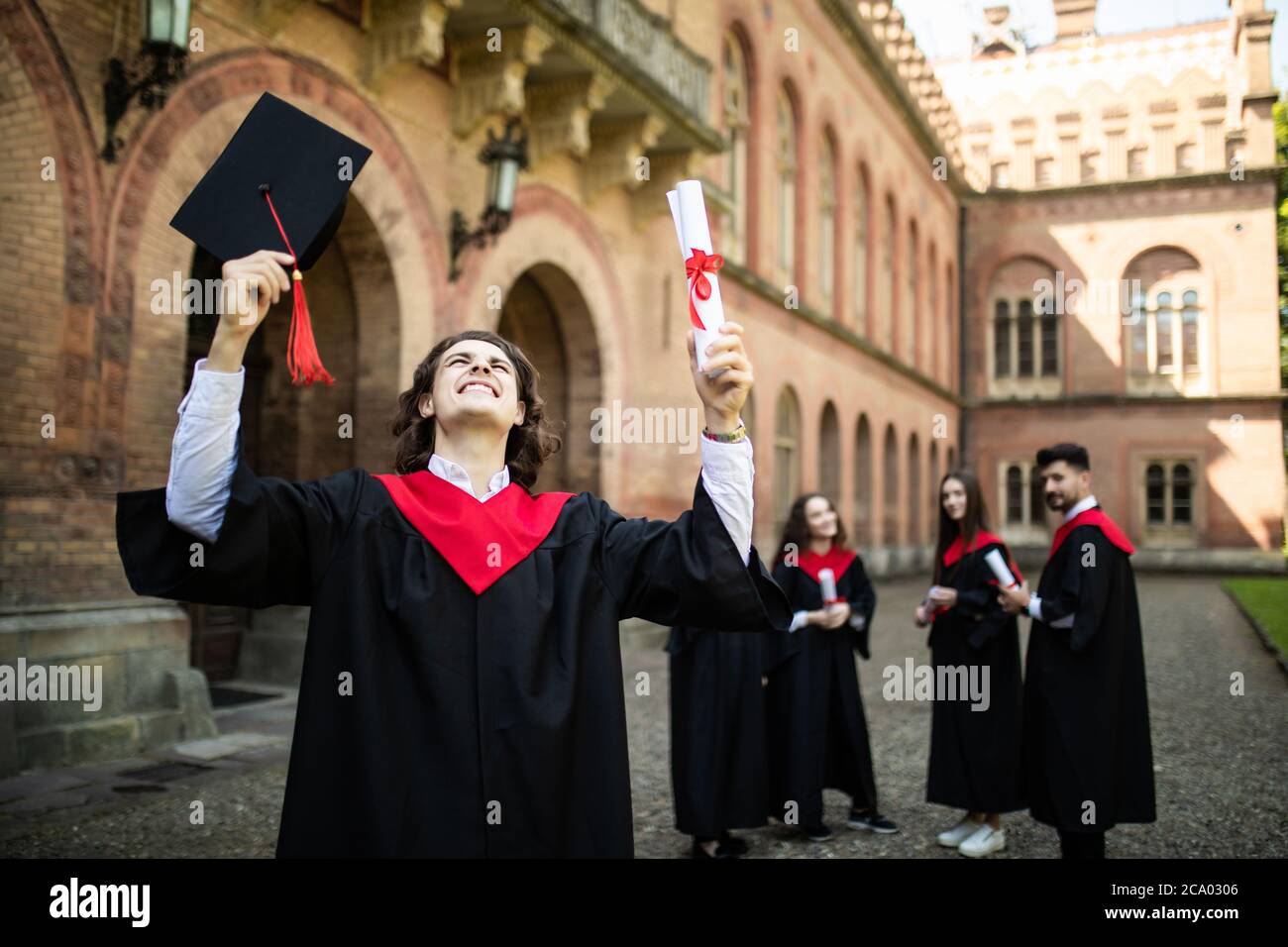 Close-up of a smiling graduate smiling with her friends in background ...
