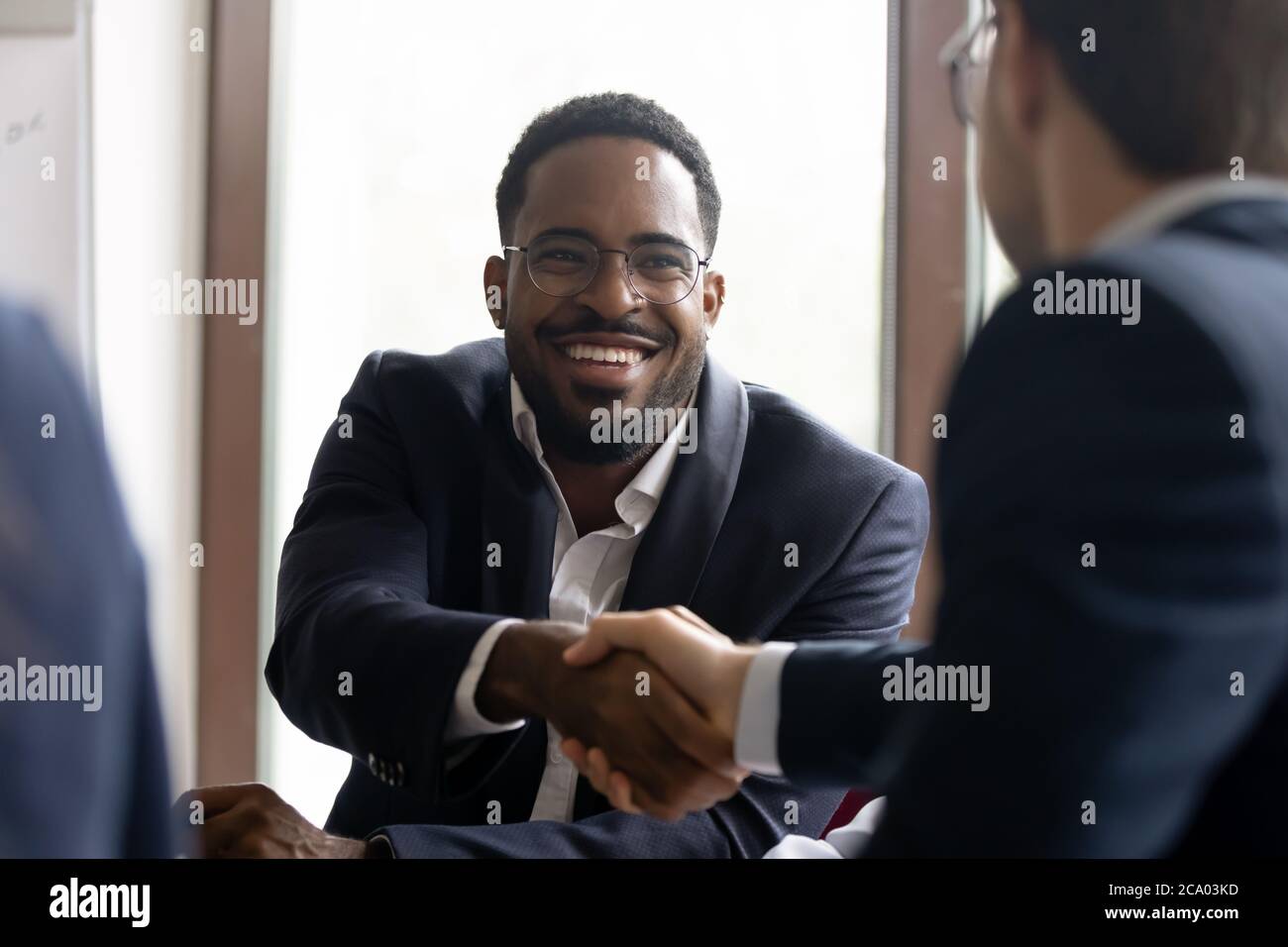 Multiracial businessmen express respect shake hands start negotiations ...