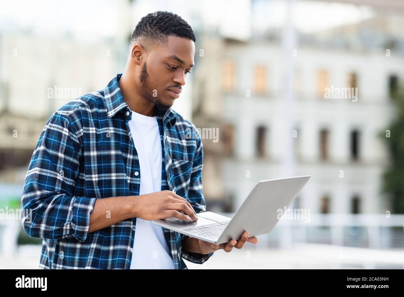 Black man using laptop, standing in city Stock Photo - Alamy