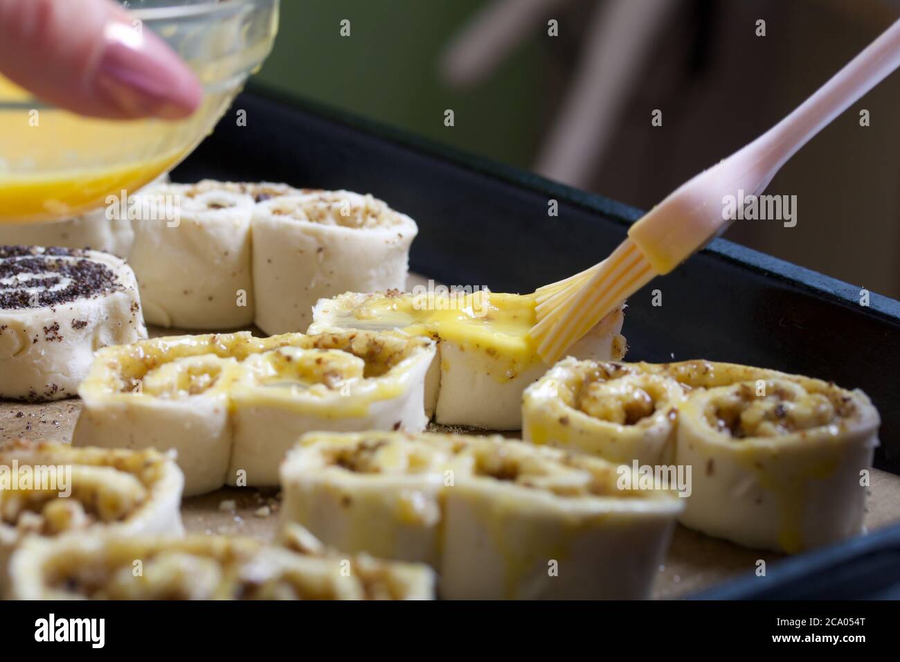 A woman smears an egg on curls stuffed with poppy and walnuts. For ...