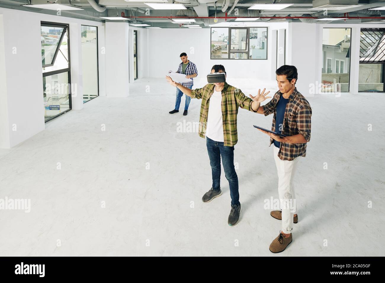 Young developers testing new virtual reality application in empty room ...