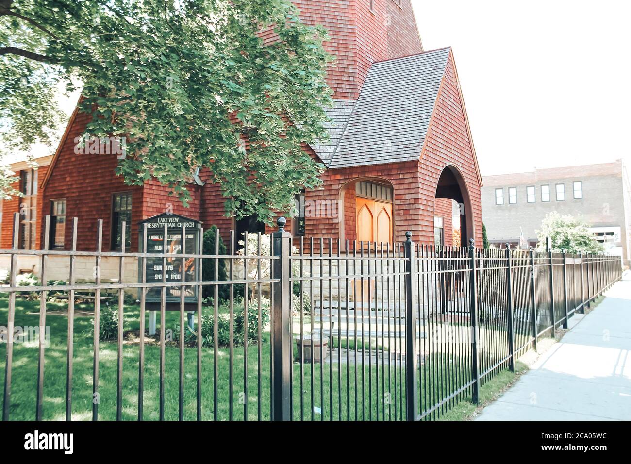 Beautiful church of red color fenced with an iron fence made of twigs ...