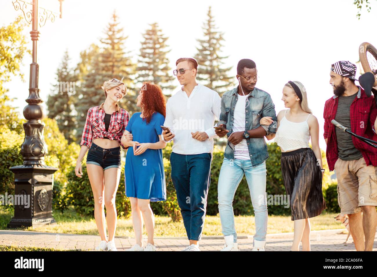 Multi-ethnic group of young cheerful people bonding outdoors, having a ...