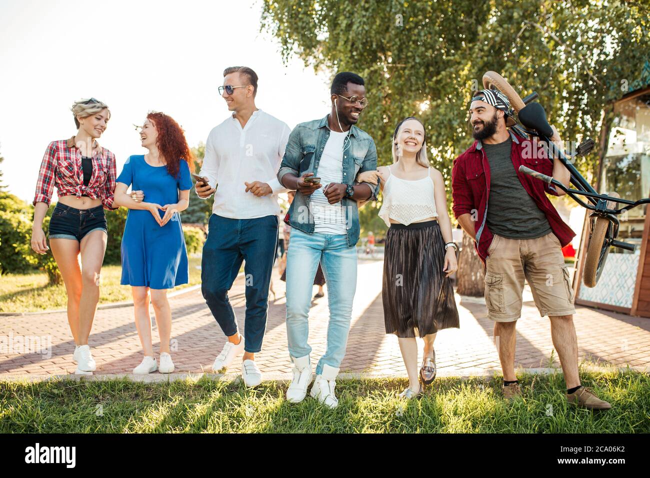 Happy adult guys and girls in casual wear enjoying a long walk ...