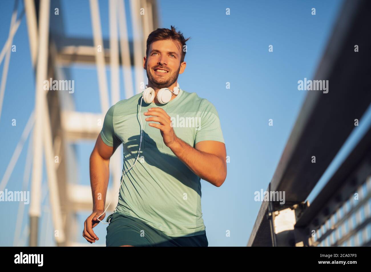 Young man is jogging outdoor on bridge in the city Stock Photo - Alamy