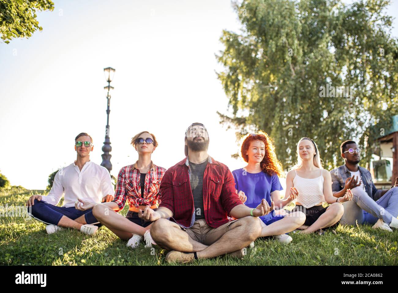 Yoga at park. Interracial friends meditating and spending their leisure ...