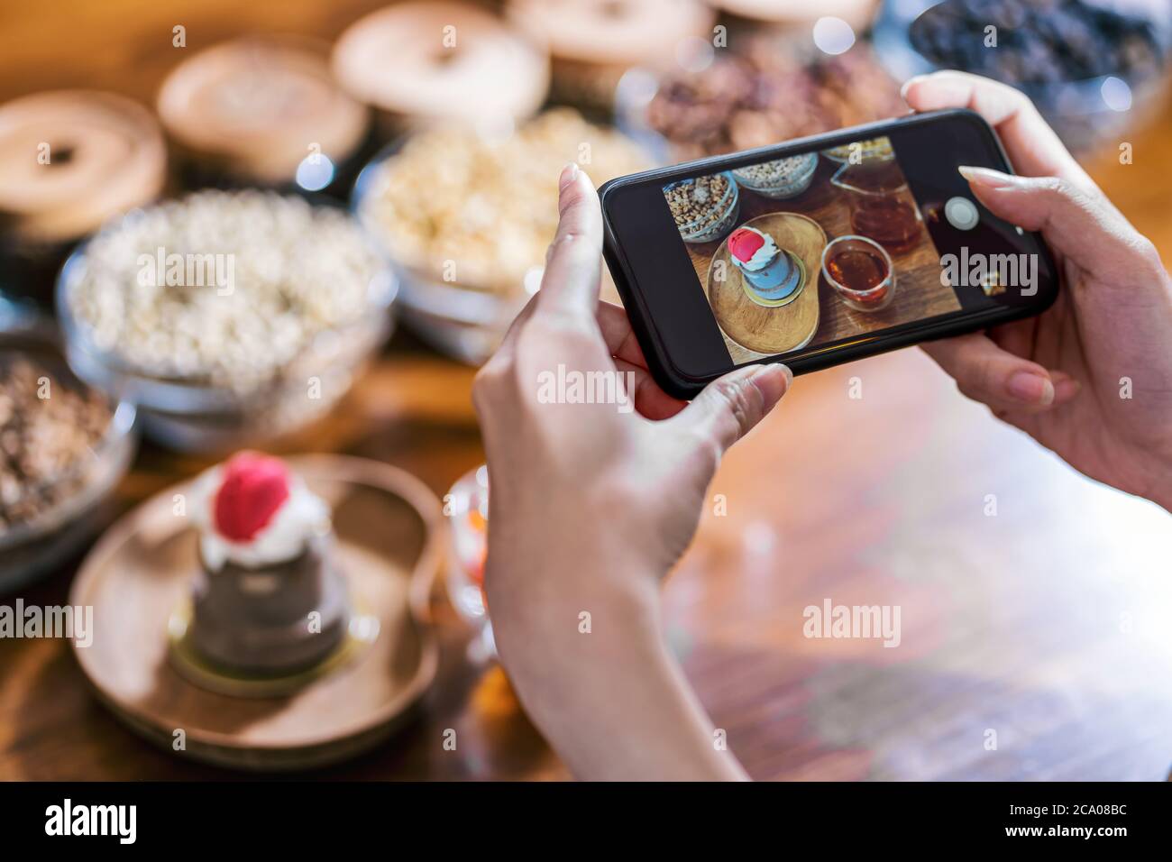 Closeup mobile phone taking photo of cupcake bakery with honey serving ...